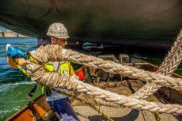 Met hun kleine bootjes leggen deze mannen immense schepen aan de kade ...