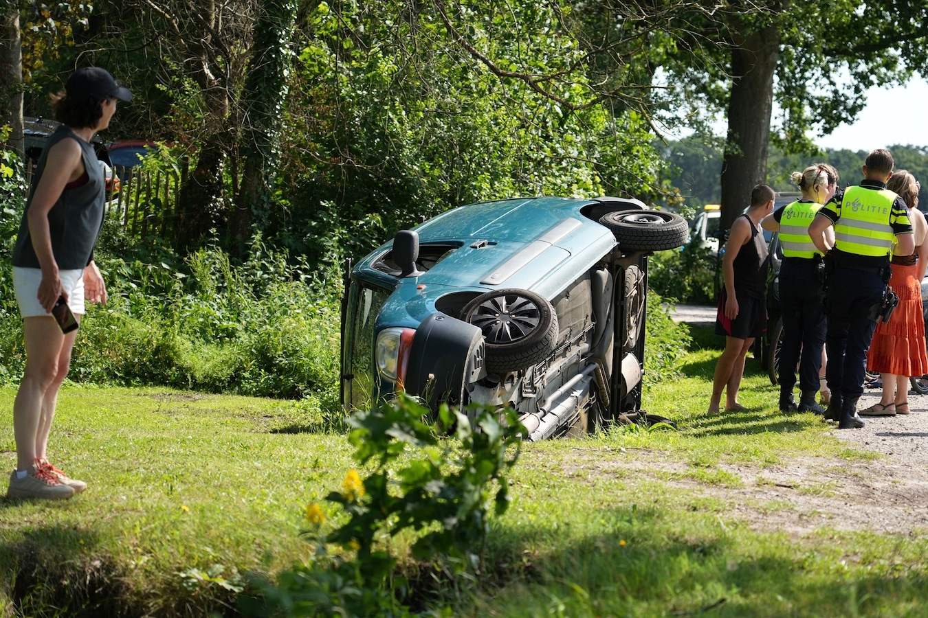 Auto belandt op zijkant in greppel in Oosterhout, omstanders helpen ...