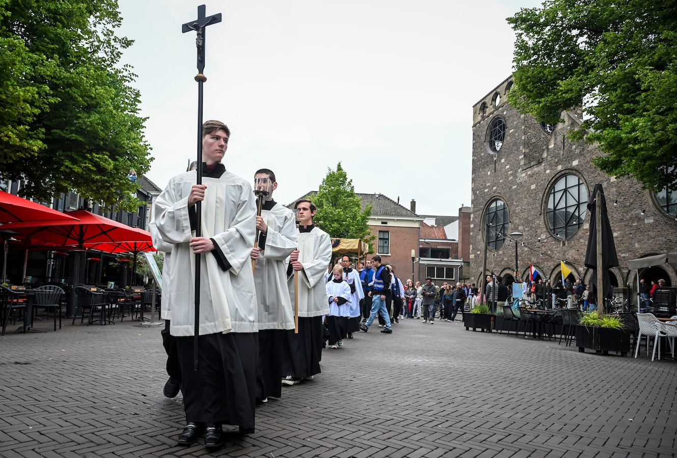 Winkelend publiek kijkt verbaasd naar religieuze stoet door Enschede ...