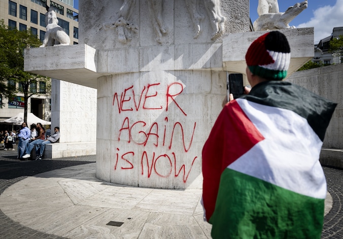 Betoger spuit leus op Nationaal Monument op de Dam tijdens demonstratie ...