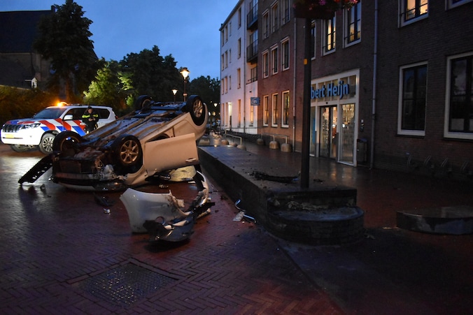 Auto op de kop na botsing met stenen rand voor supermarkt in Bemmel ...