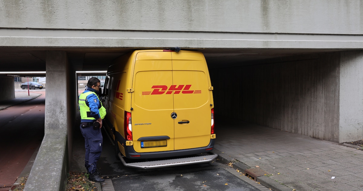 DHL-bezorger gaat tegen verkeer in en rijdt zijn bestelbus klem onder ...