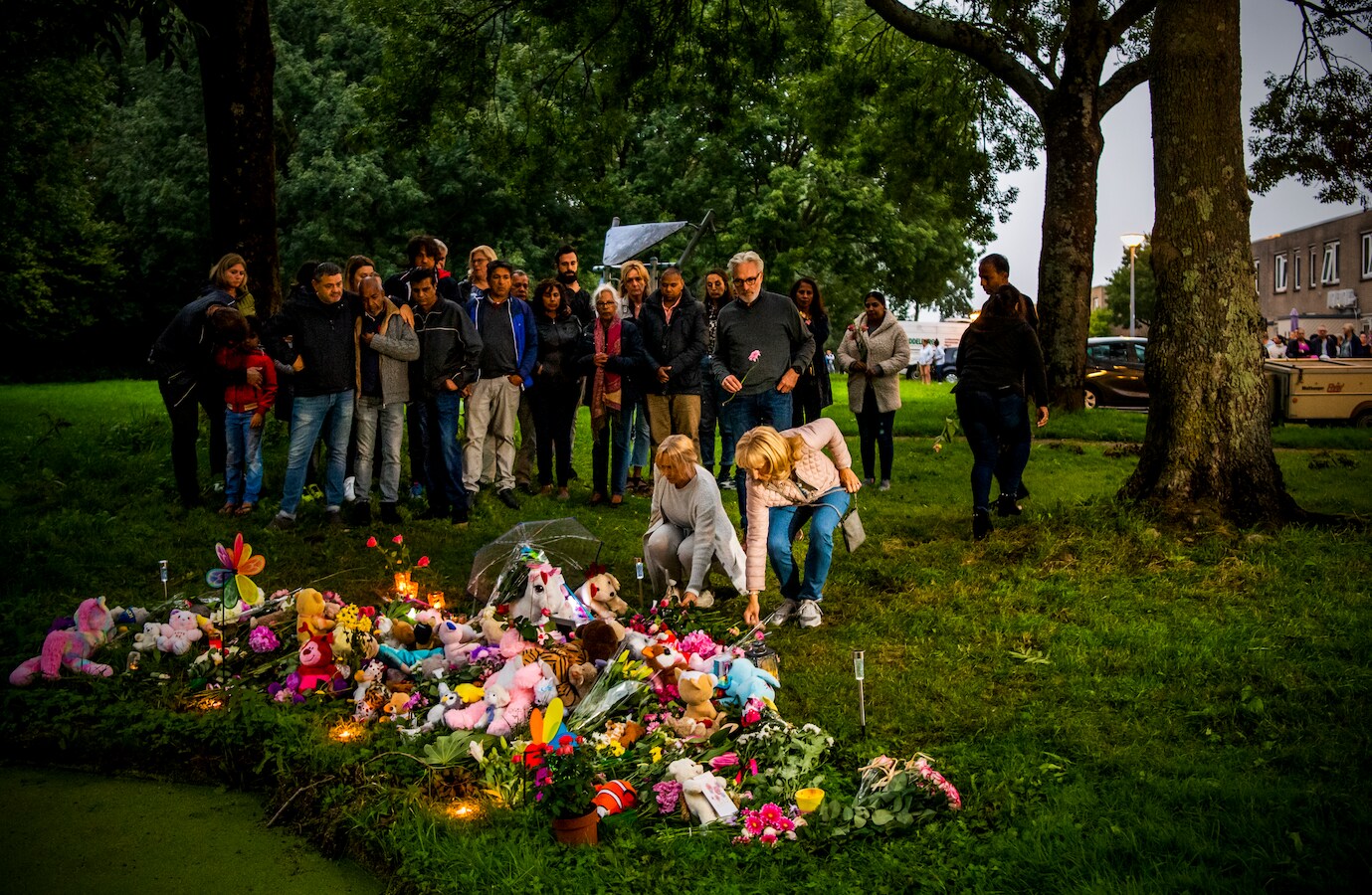 Roze bloemen en knuffels in emotionele stille tocht voor verdronken ...